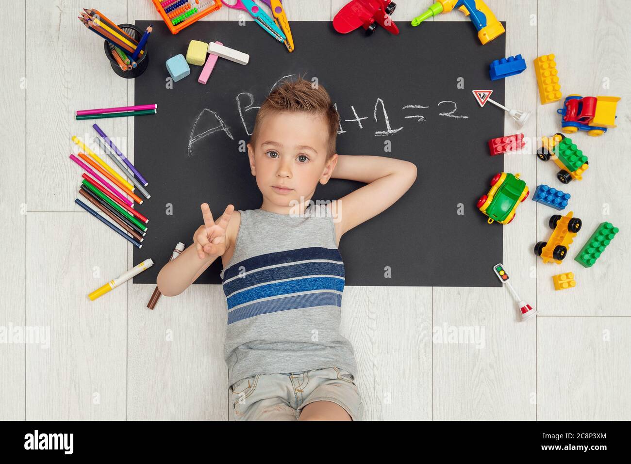 Cheerful smiling little boy lies on his drawing Stock Photo - Alamy