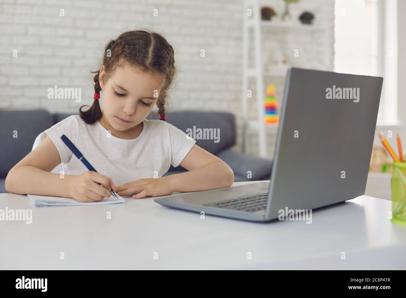 Online education and home schooling. Smart little girl taking notes in ...