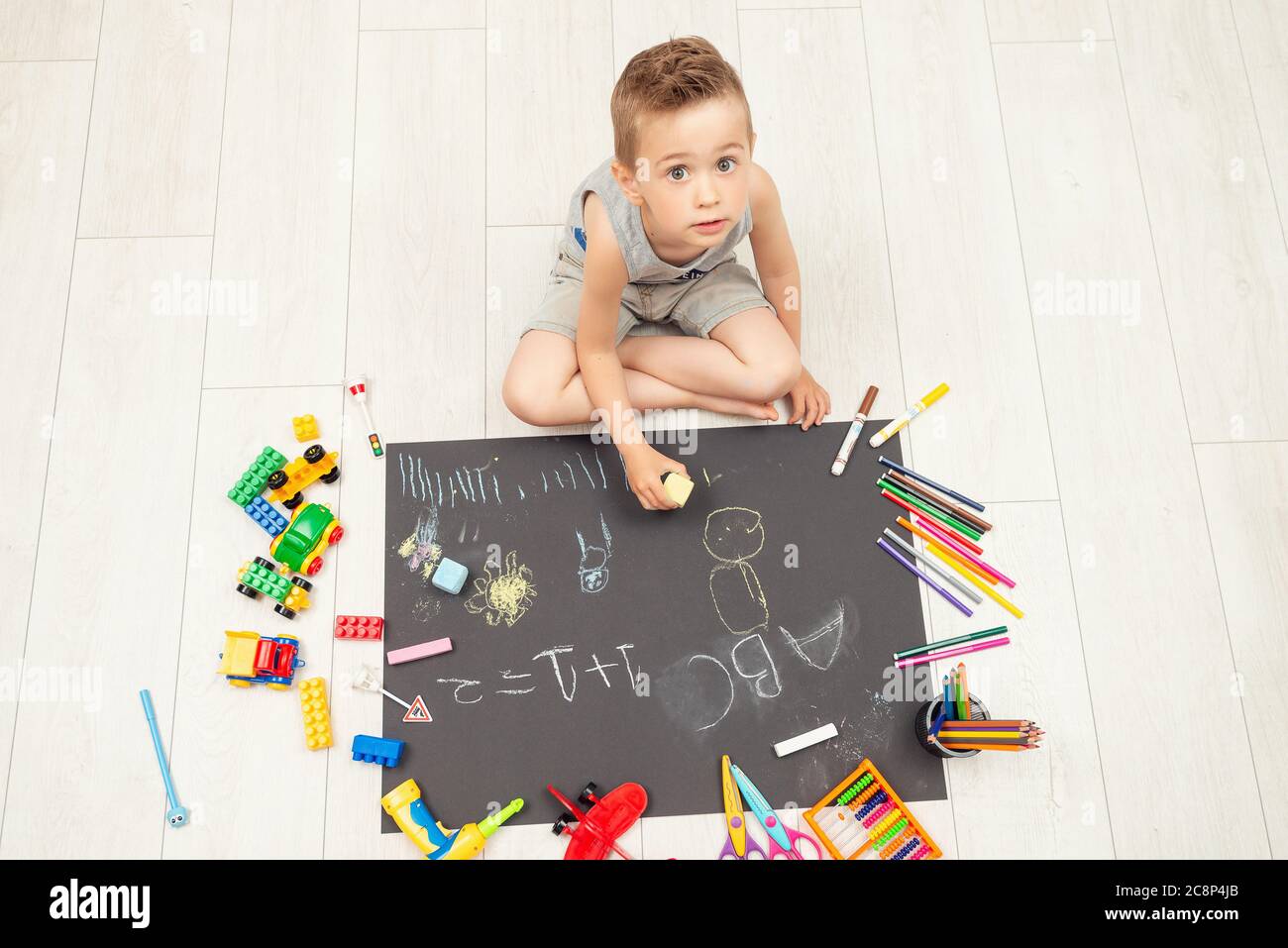 Little child sitting alone using chalk painting on black paper Stock ...