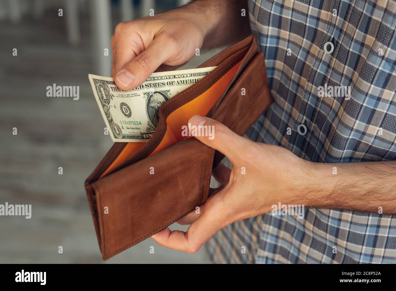 A close-up of a man's hand pulls out a 1 US dollar bill in his wallet ...