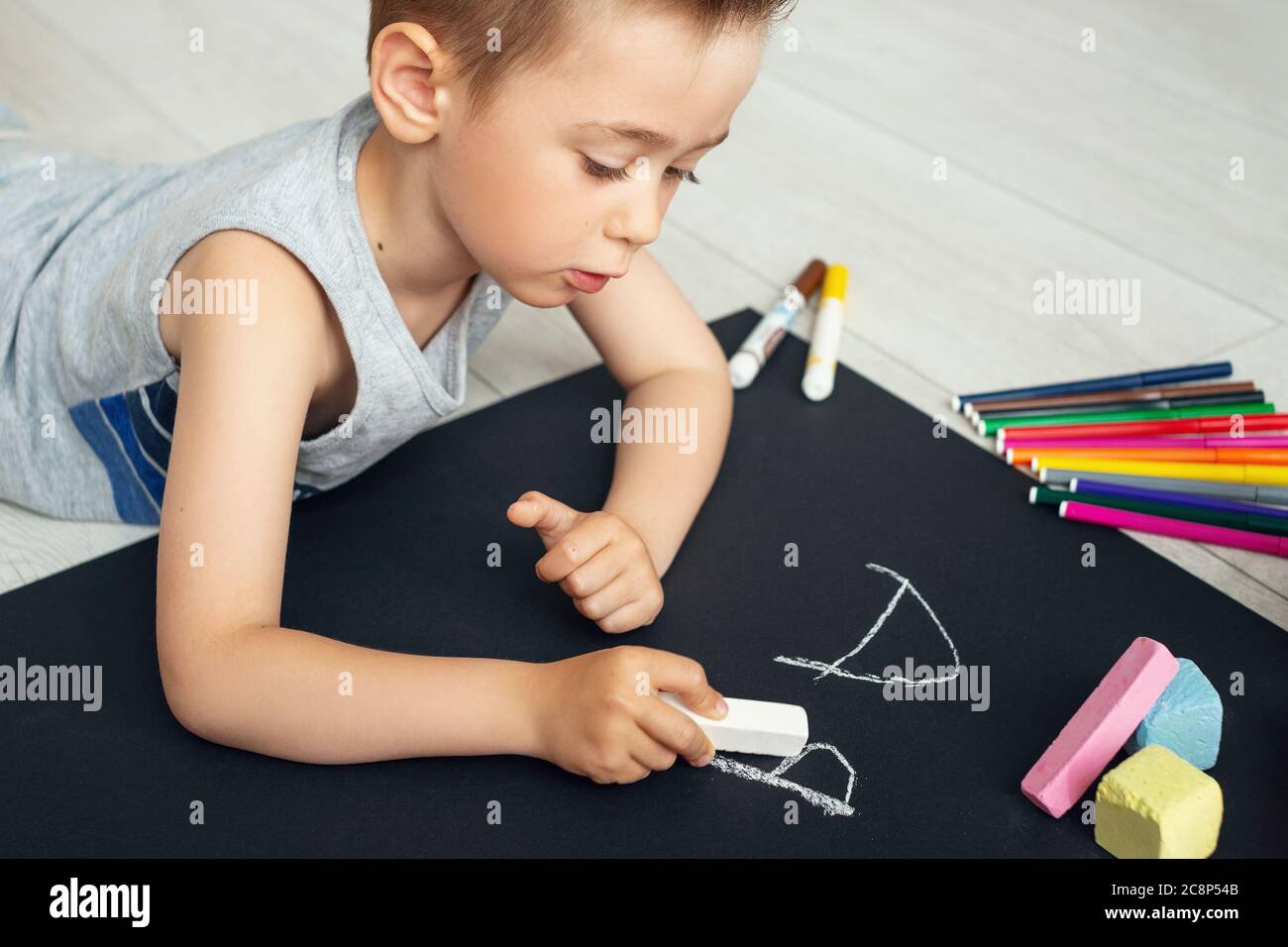 Preschool boy writing letters. Close-up chalk in the hand of child. Boy ...