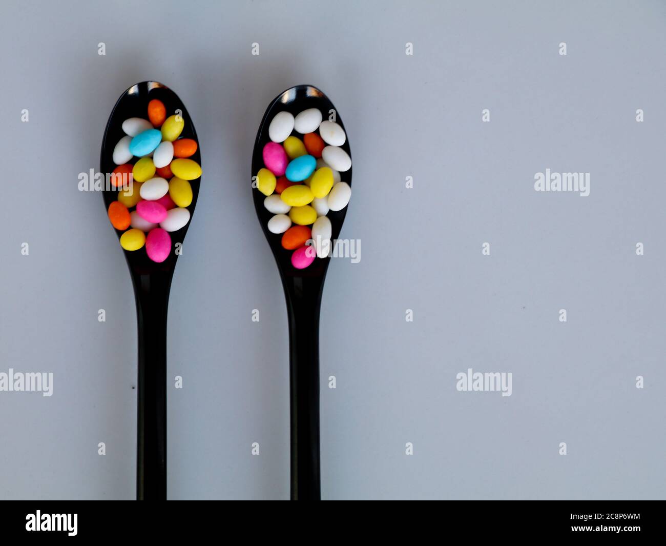 Multi colored sweet fennel sugar candy in black spoons against white ...