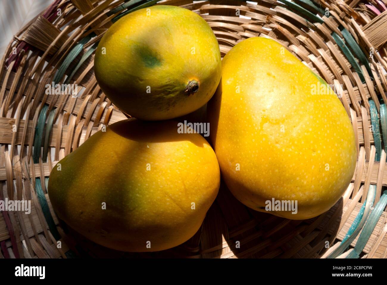 a fresh juicy mango isolated on bamboo texture background water drops ...