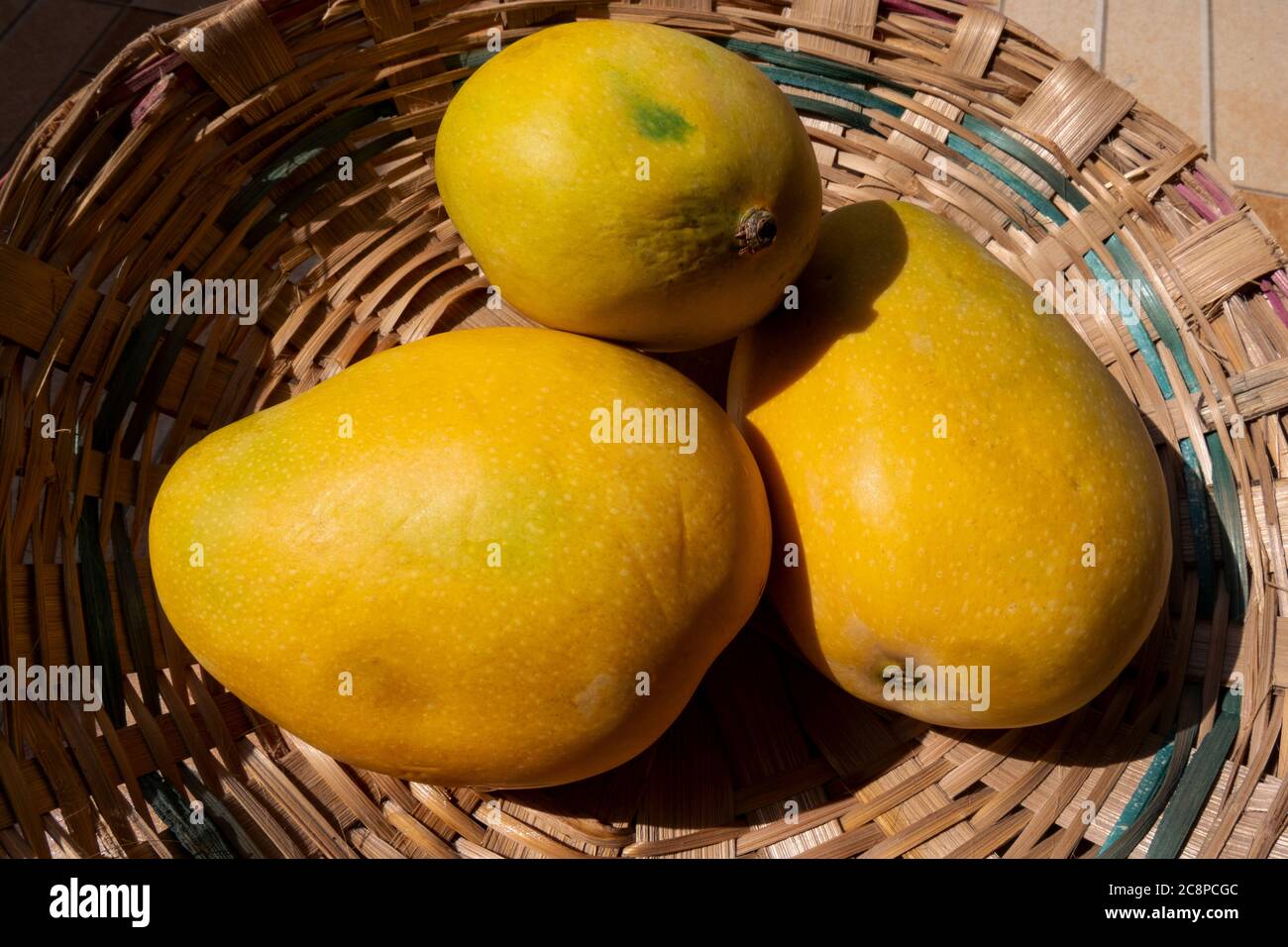 a fresh juicy mango isolated on bamboo texture background water drops ...