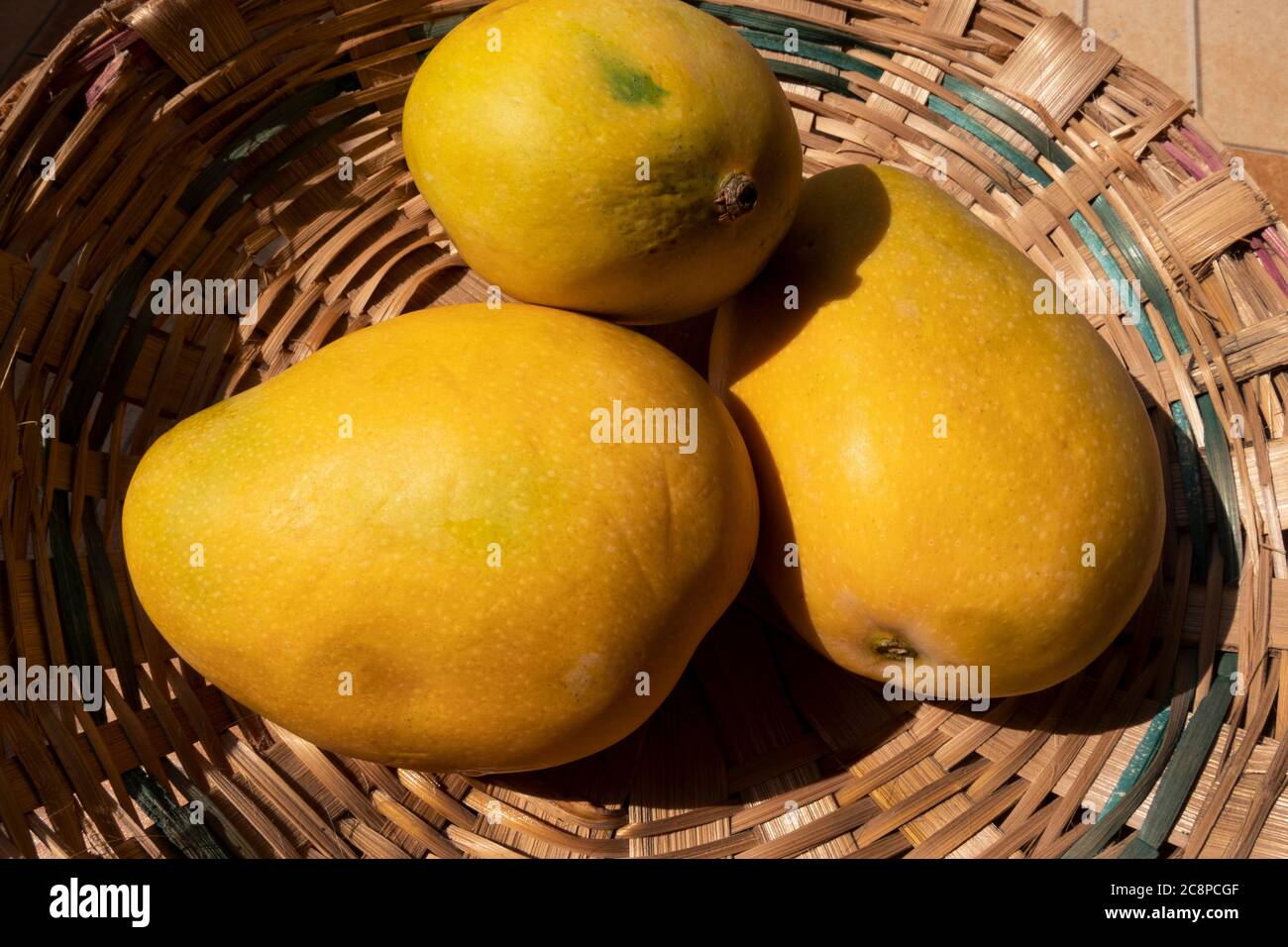 a fresh juicy mango isolated on bamboo texture background water drops ...