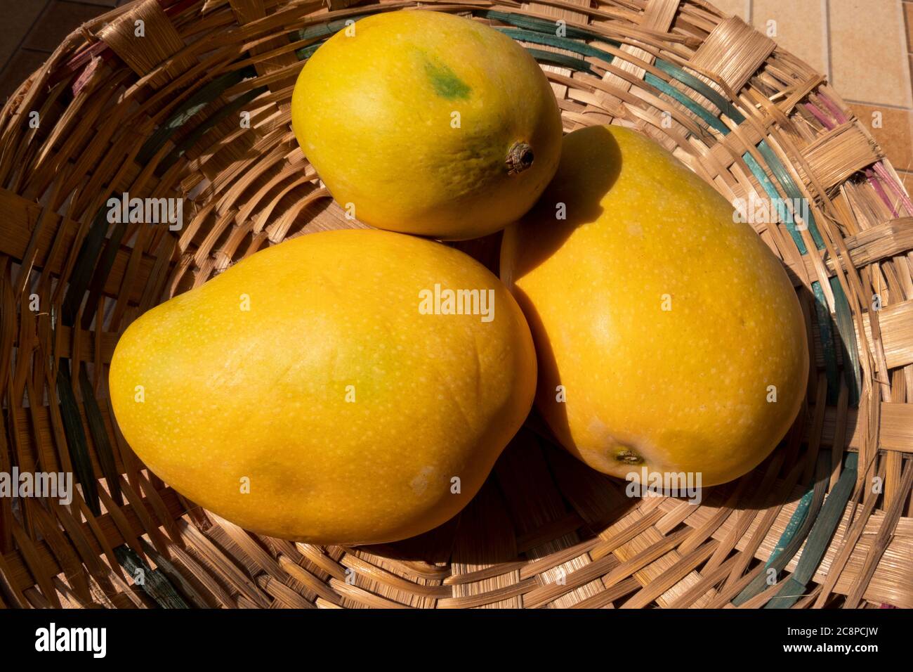 a fresh juicy mango isolated on bamboo texture background water drops ...