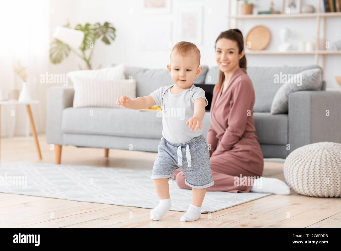 First Steps. Adorable smiling baby boy learning how to walk at home ...