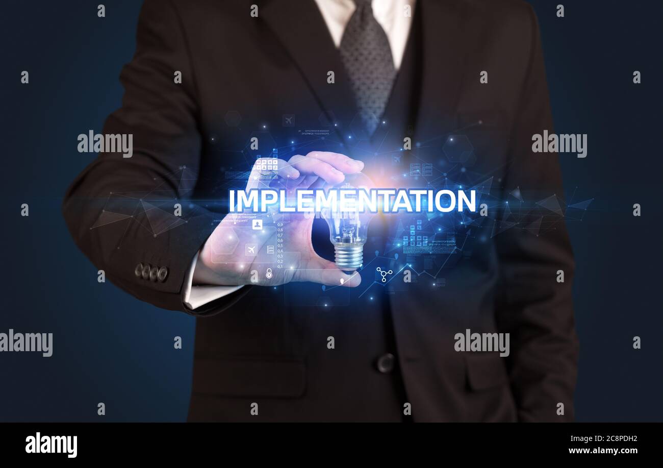 Businessman holding light bulb with IMPLEMENTATION inscription ...