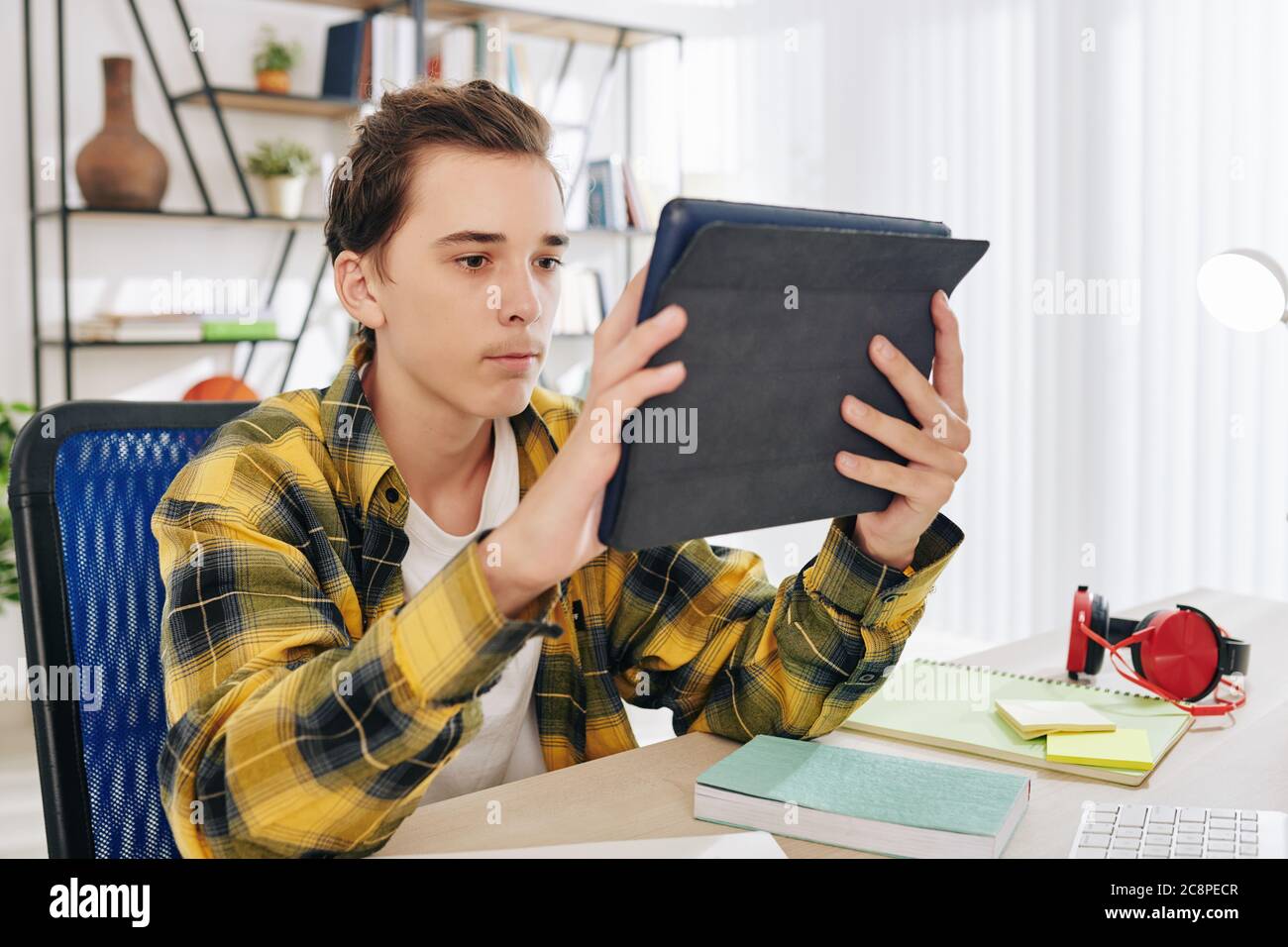 Serious teenage boy watching video, reading article or using ...
