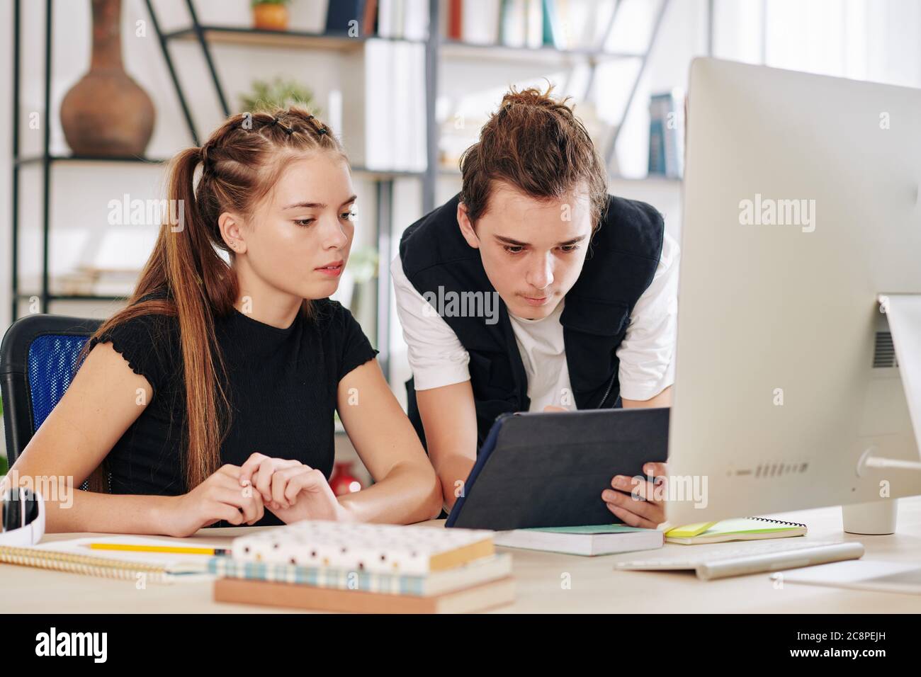 Serious teenage boy and girl working on school project together at home ...