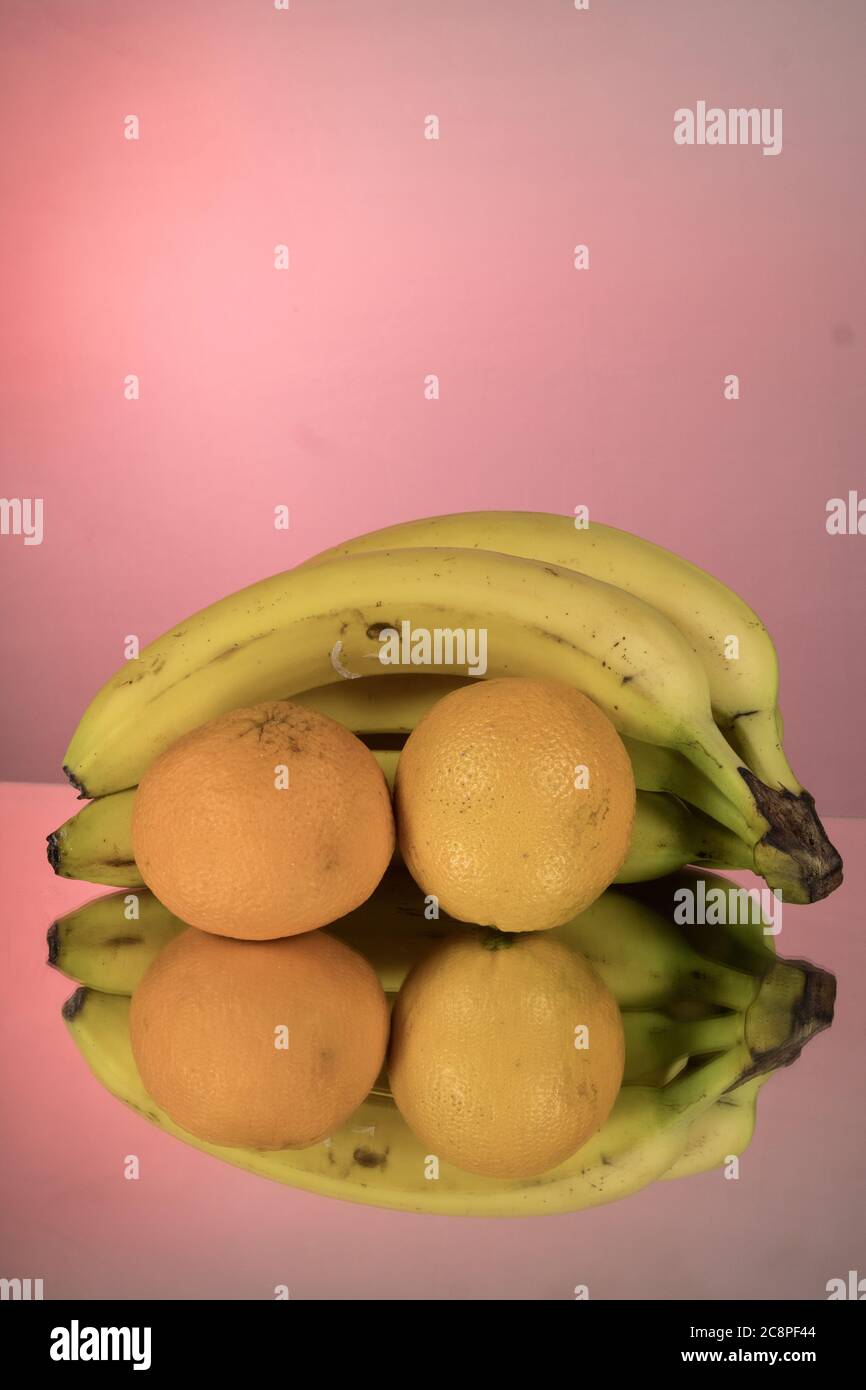 A bunch of bananas and apples on mirroring table on mirror red ...