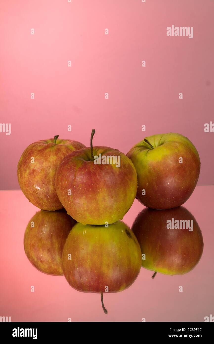 Three red apples on mirroring table on mirror red background with ...