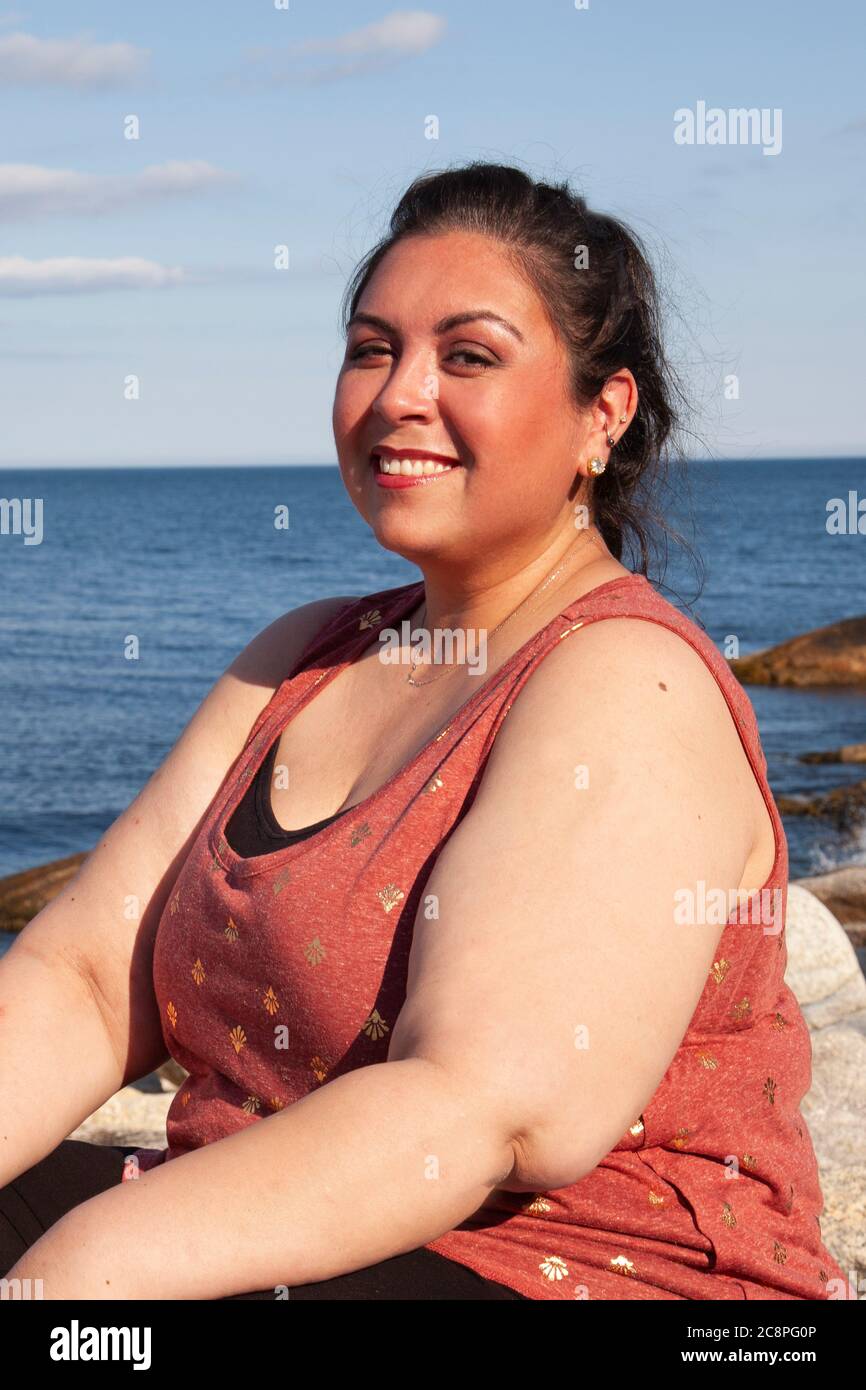 fresh real woman outdoors smiling while sitting beside the ocean in the ...