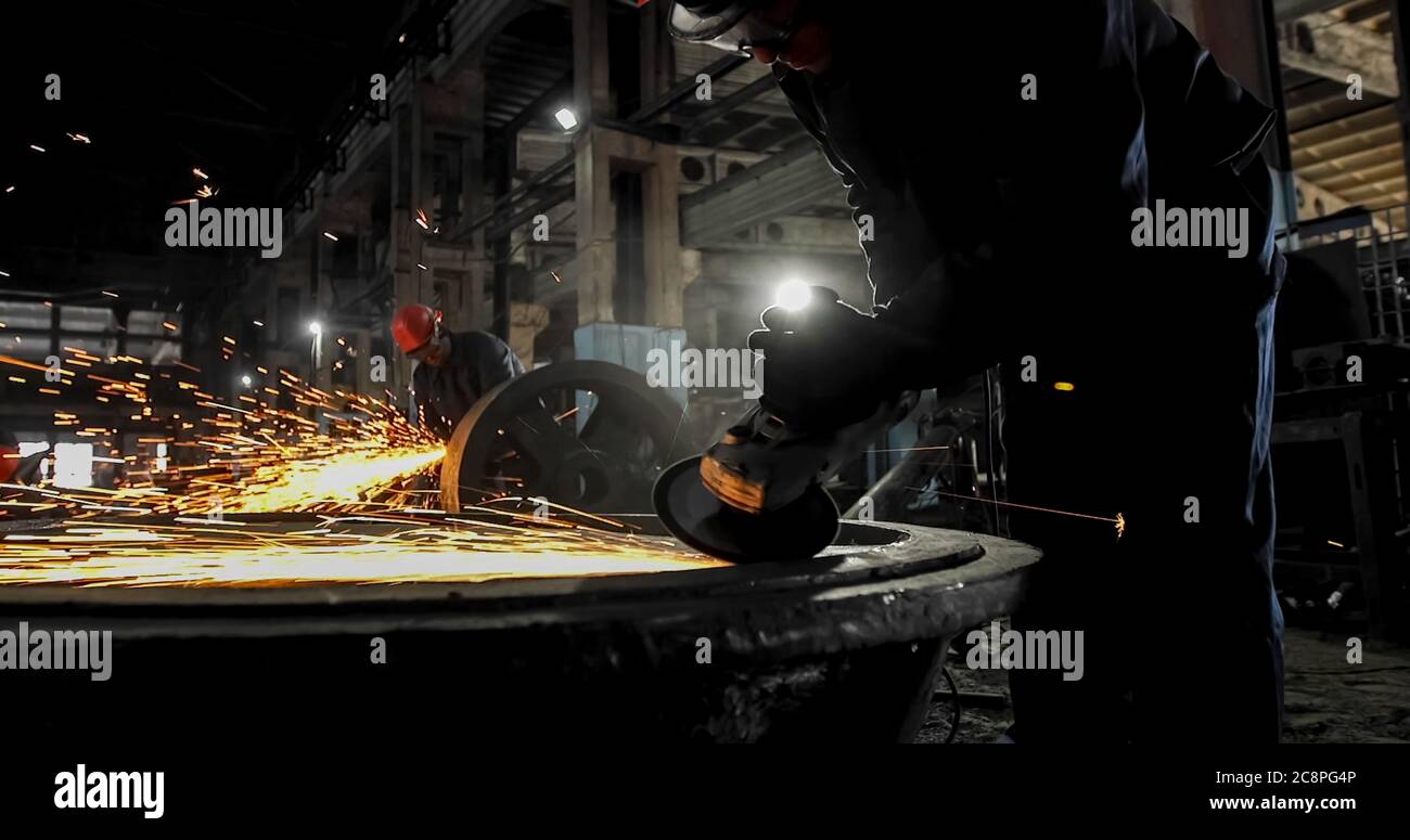Working in a mask and headphones cleans joints angle grinder on metal ...