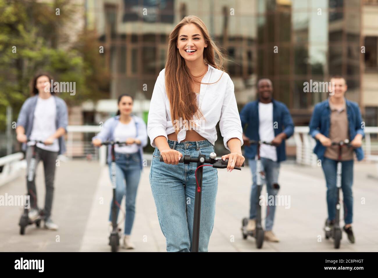Happy students having ride on electric kick scooters Stock Photo - Alamy