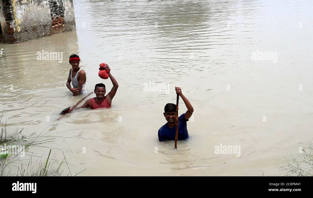 Bihar, India. 26th July, 2020. Villagers wade through flood water in ...