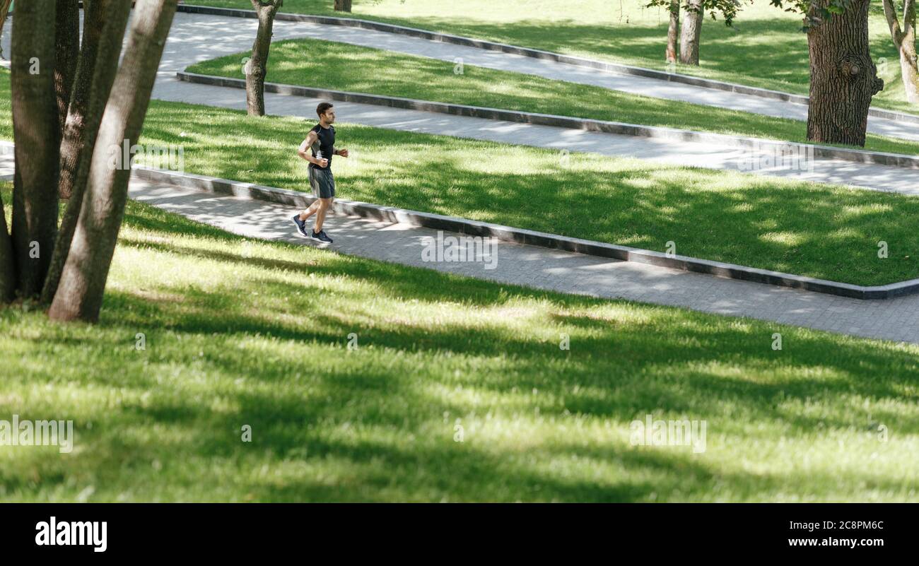 Outdoor physical activity. Man in sportswear runs along the track Stock ...