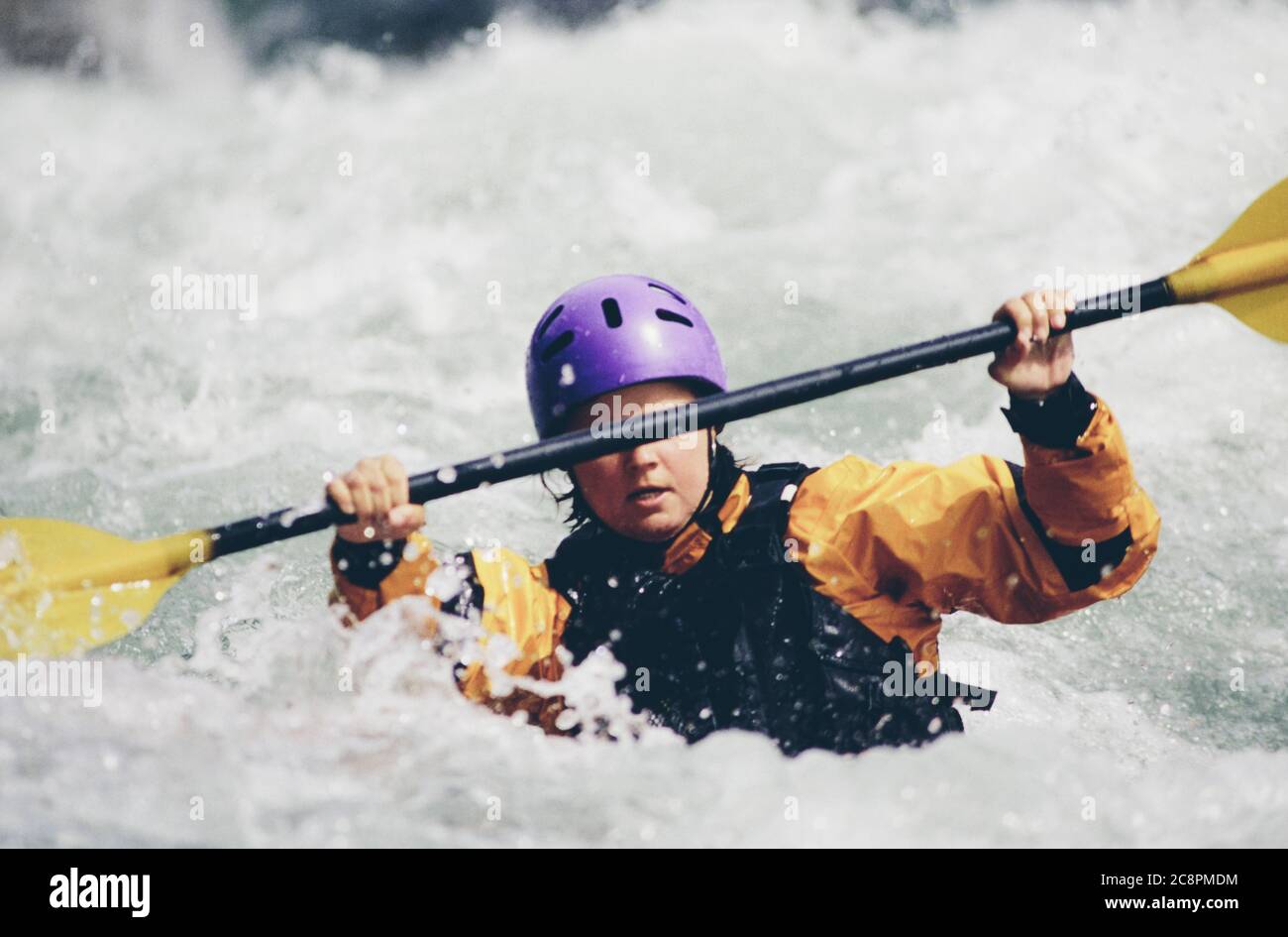 Female whitewater kayaker paddling rapids and surf on a fast flowing ...