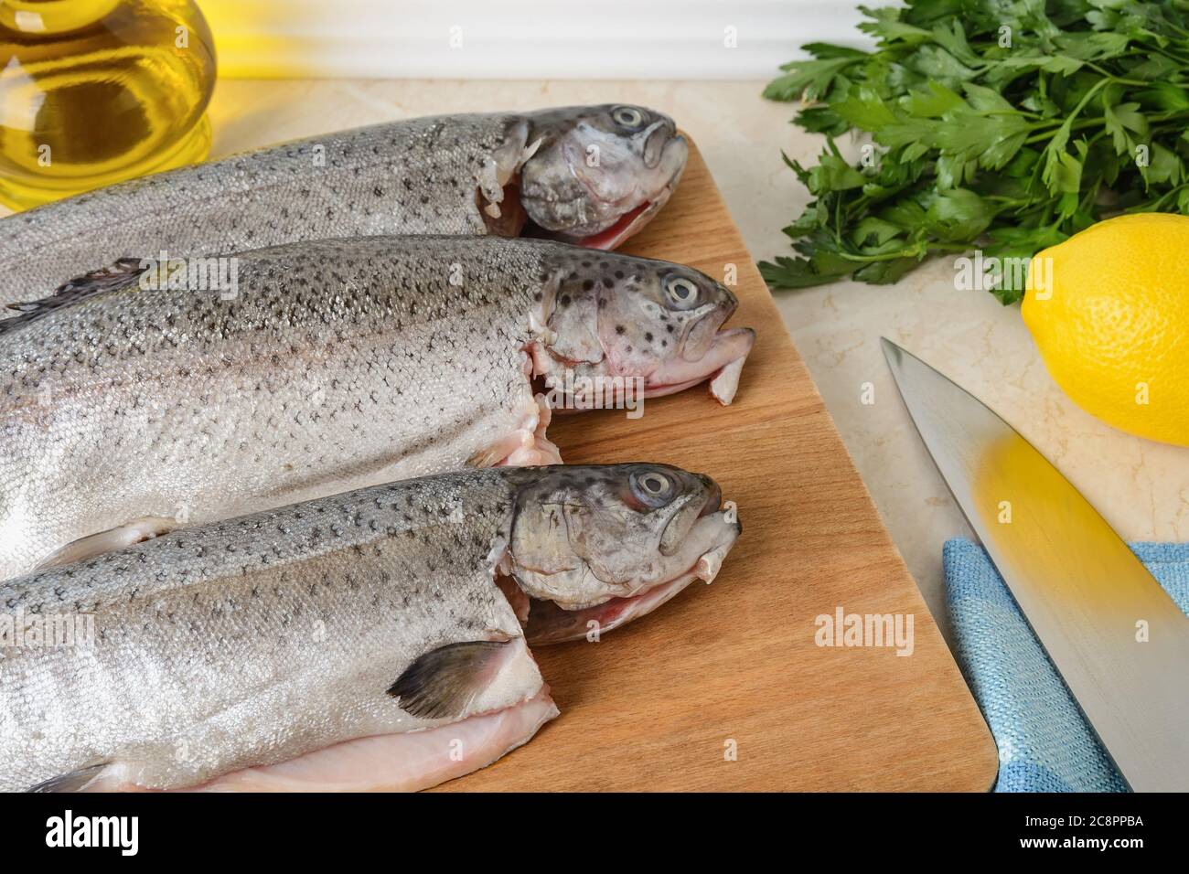 Close-up of three raw gutted trout fishes on a wood cutting board ...