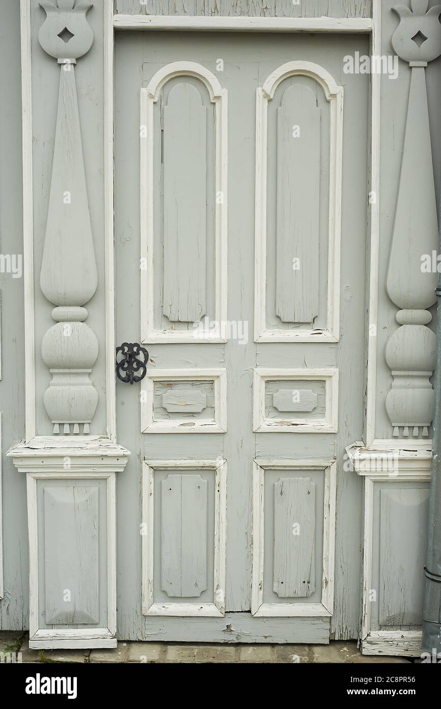 Old wooden doors decorated with figurines carved from wood. An old ...