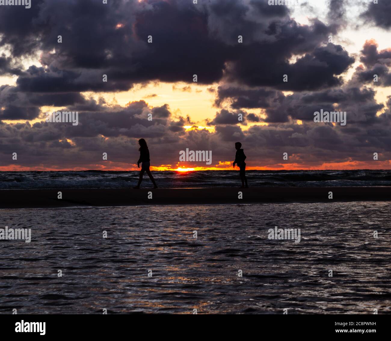 Two kids walking on a sandbar during sunset Stock Photo - Alamy