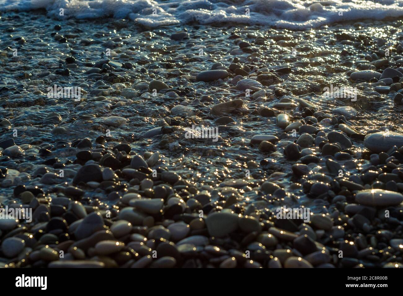 pebble stones on the sea beach, the rolling waves of the sea with foam ...