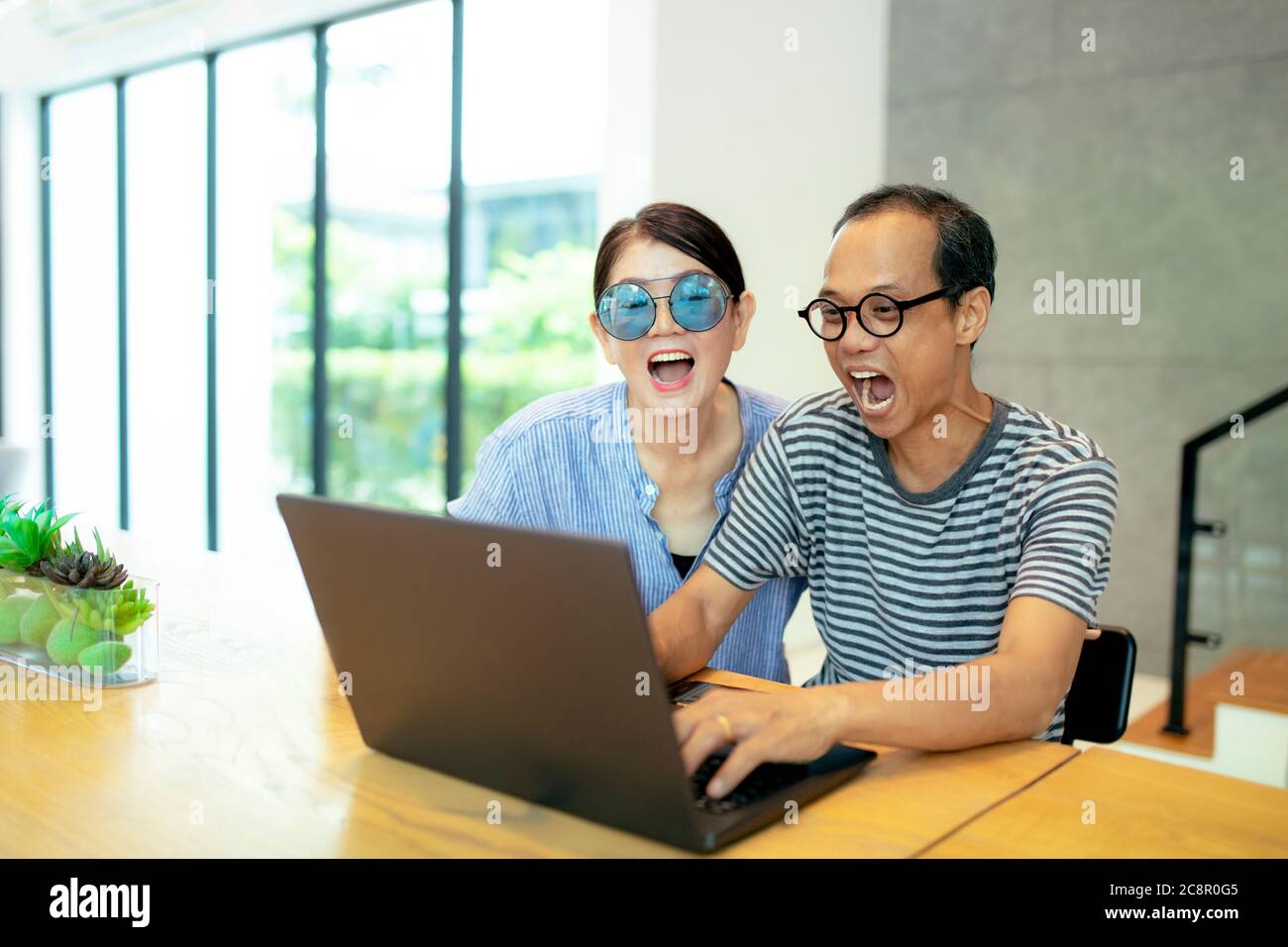 asian man and woman make a exciting face and looking to computer screen ...