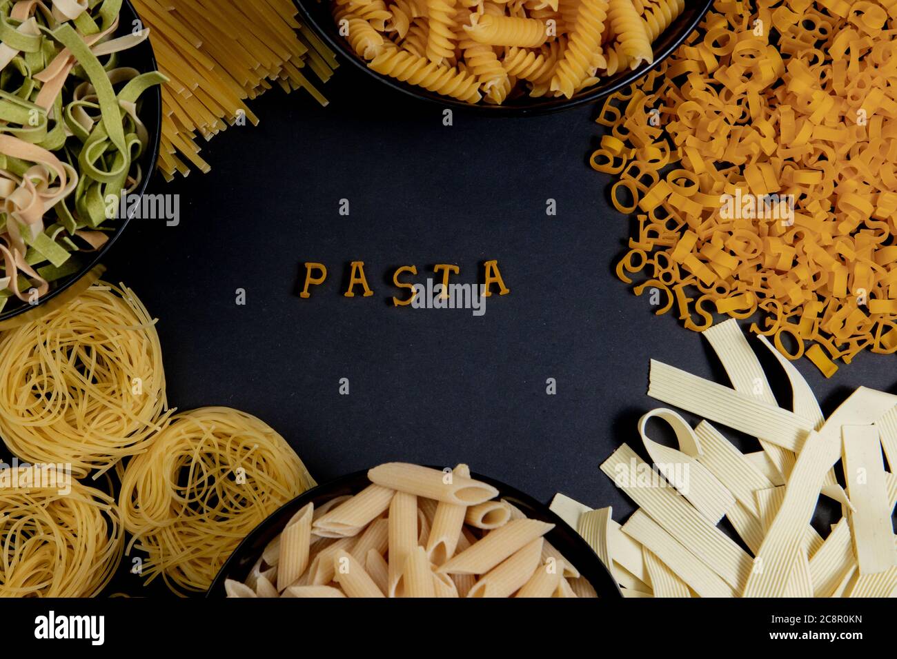 Various mix of pasta on dark background, metal spoons. Food concept ...