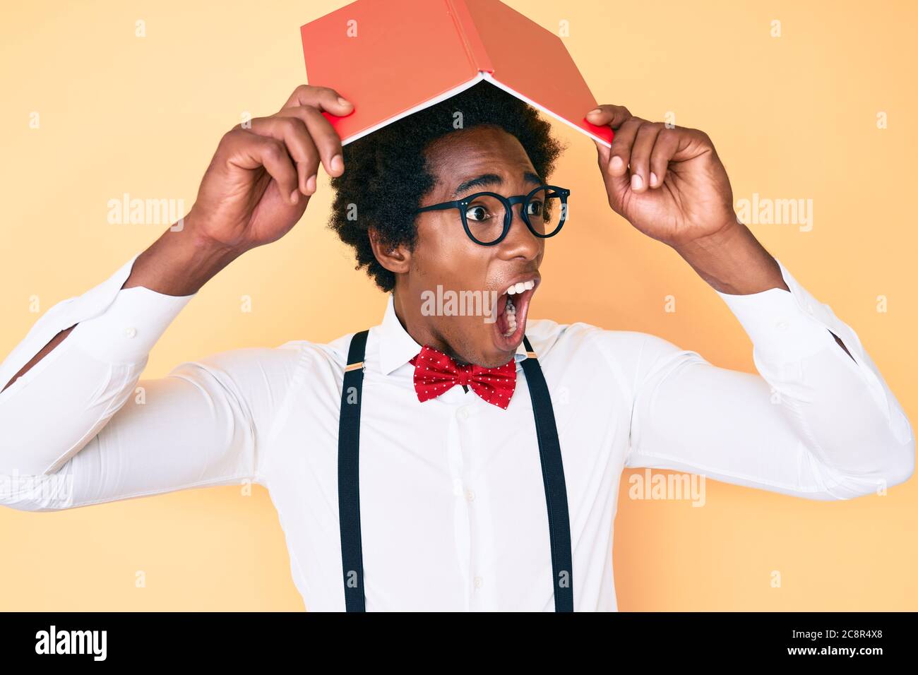 Handsome african american nerd man with afro hair holding book over ...