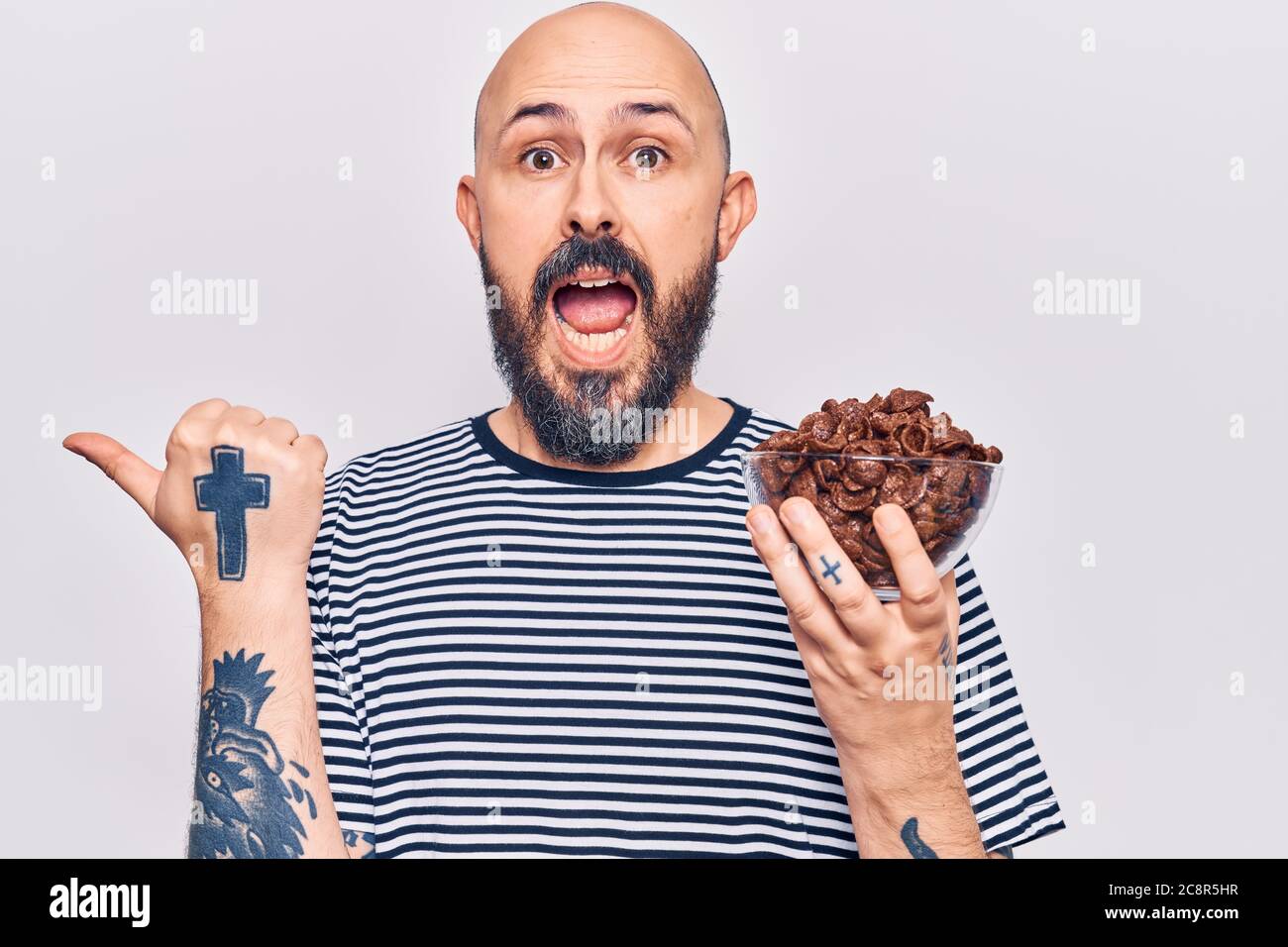 Young handsome man holding chocolate cereals pointing thumb up to the ...