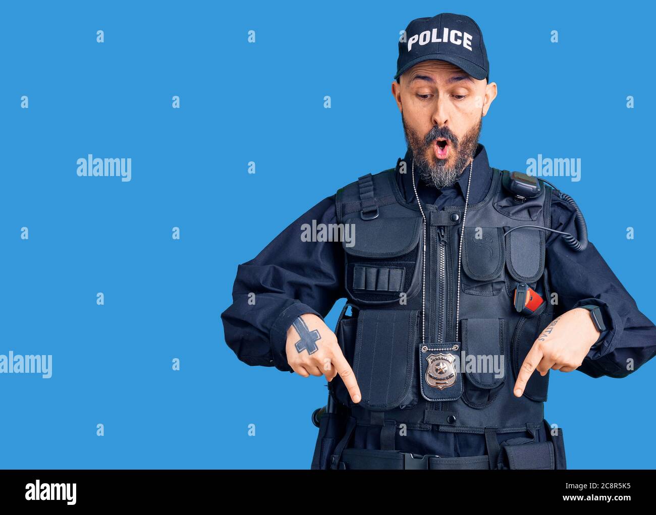 Young handsome man wearing police uniform pointing down with fingers ...