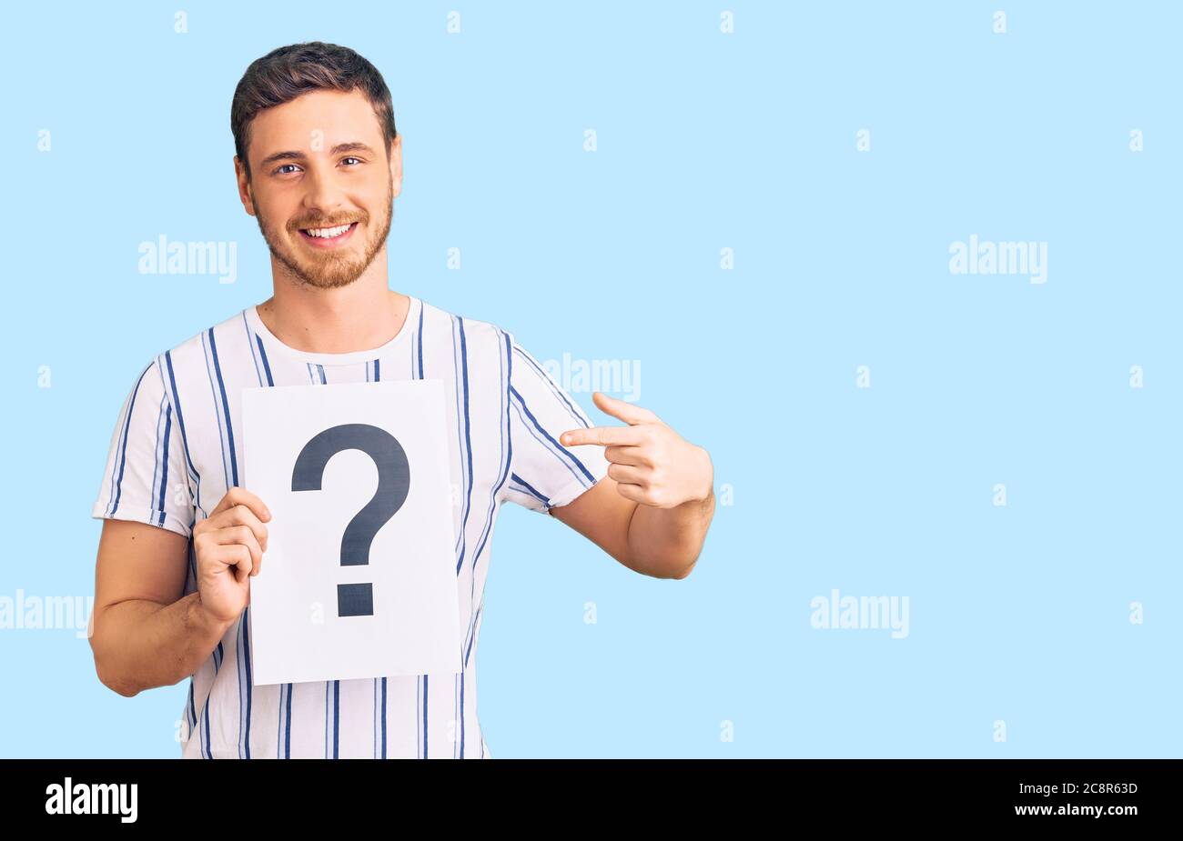 Handsome young man with bear holding question mark smiling happy ...