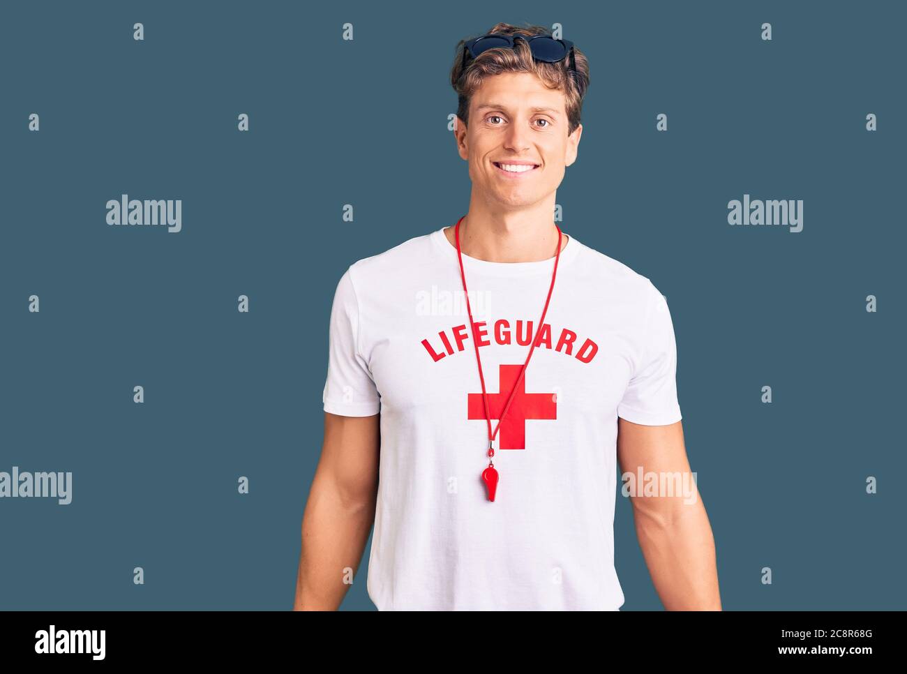 Young handsome man wearing lifeguard t shirt and whistle looking ...