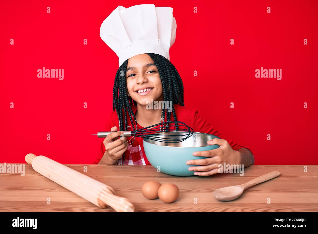 Young african american girl child with braids cooking using baker whisk ...