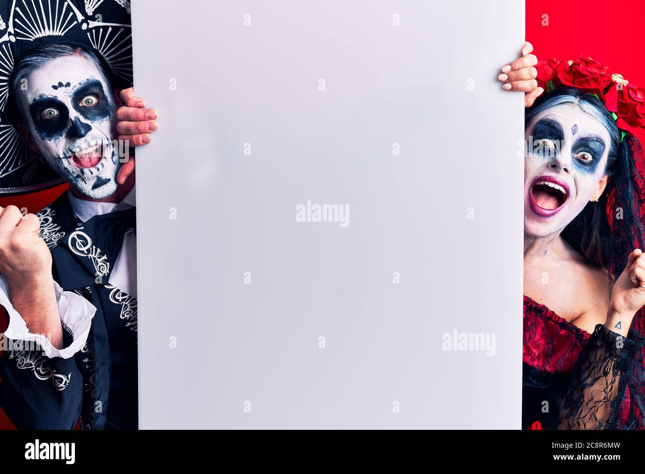 Young couple wearing mexican day of the dead costume holding blank ...