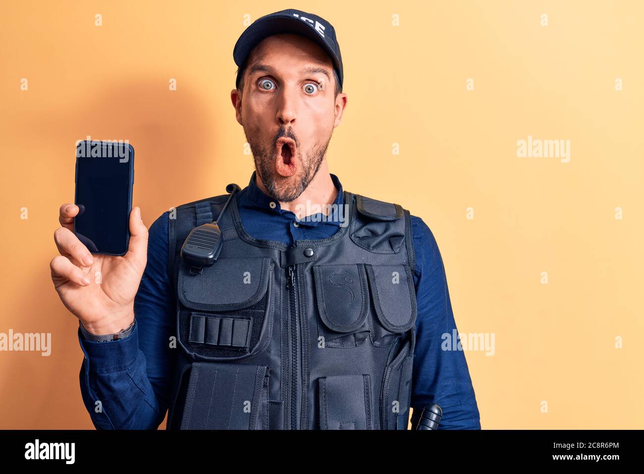 Handsome policeman wearing uniform and bulletprof holding smartphone ...