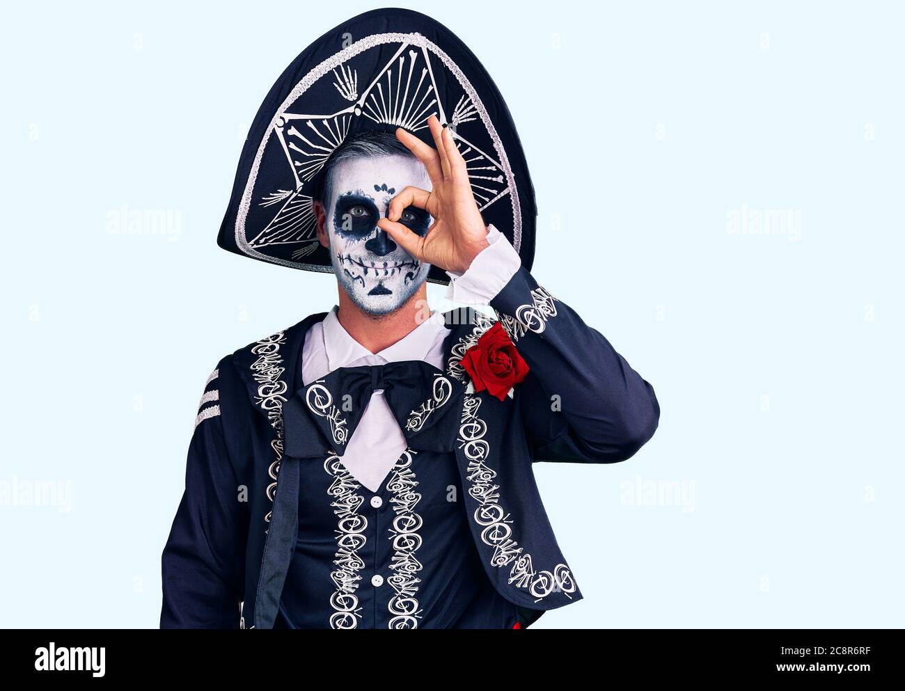 Young man wearing day of the dead costume over background doing ok ...
