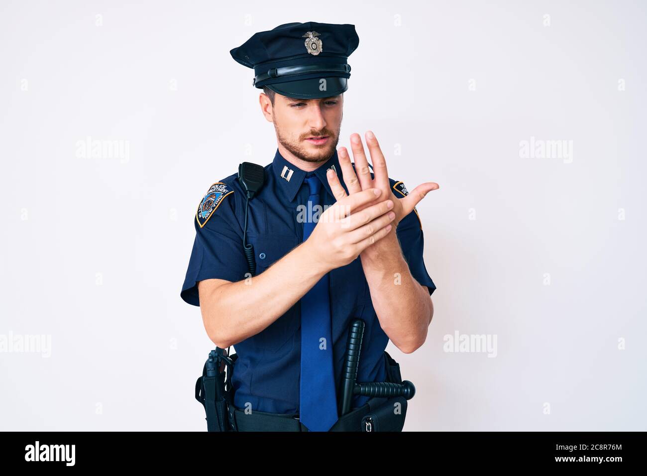 Young caucasian man wearing police uniform suffering pain on hands and ...