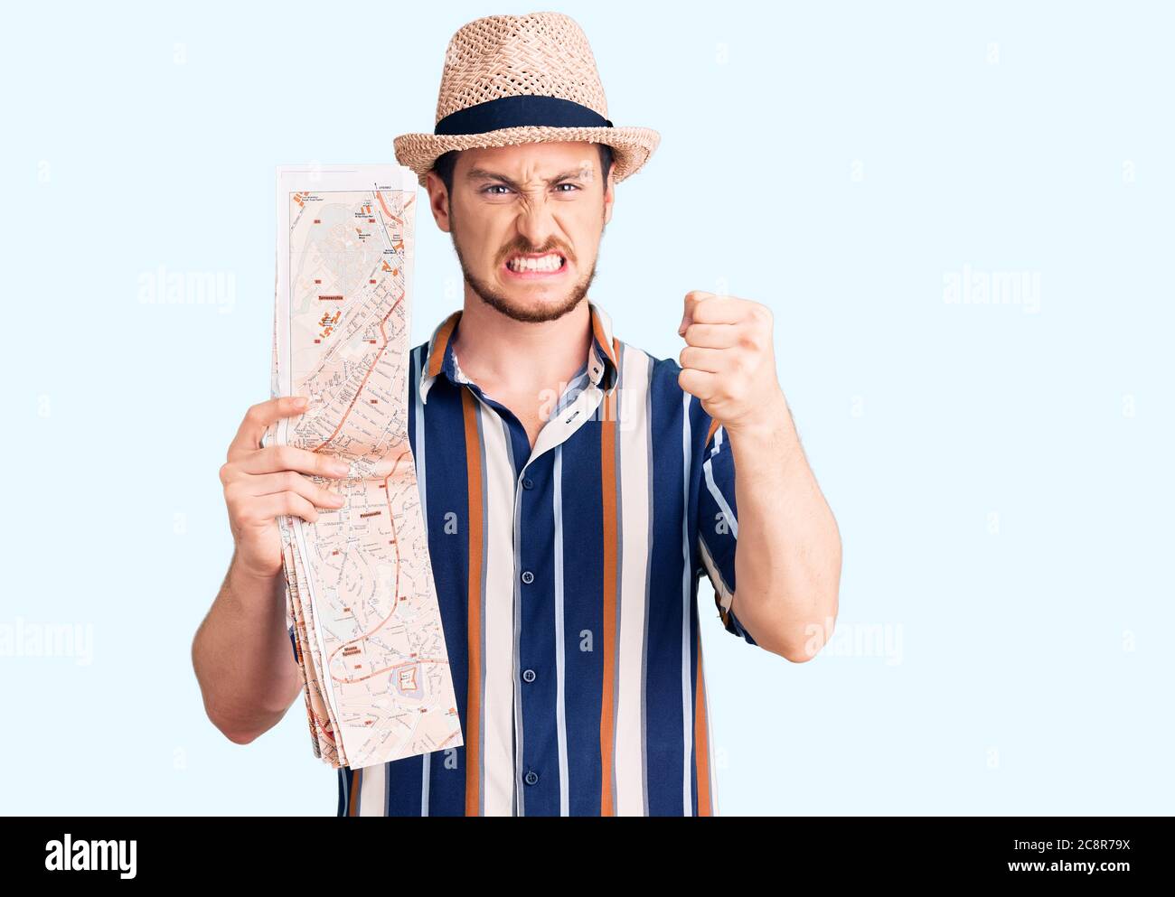 Young handsome caucasian man wearing summer hat holding city map ...