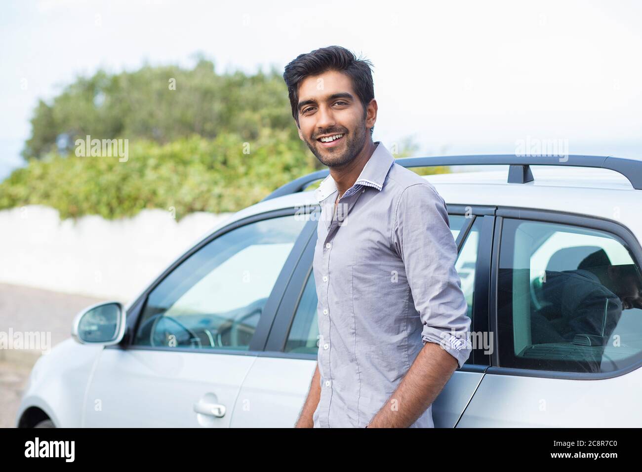 Happy man driver smiling standing by his new sport blue car isolated ...