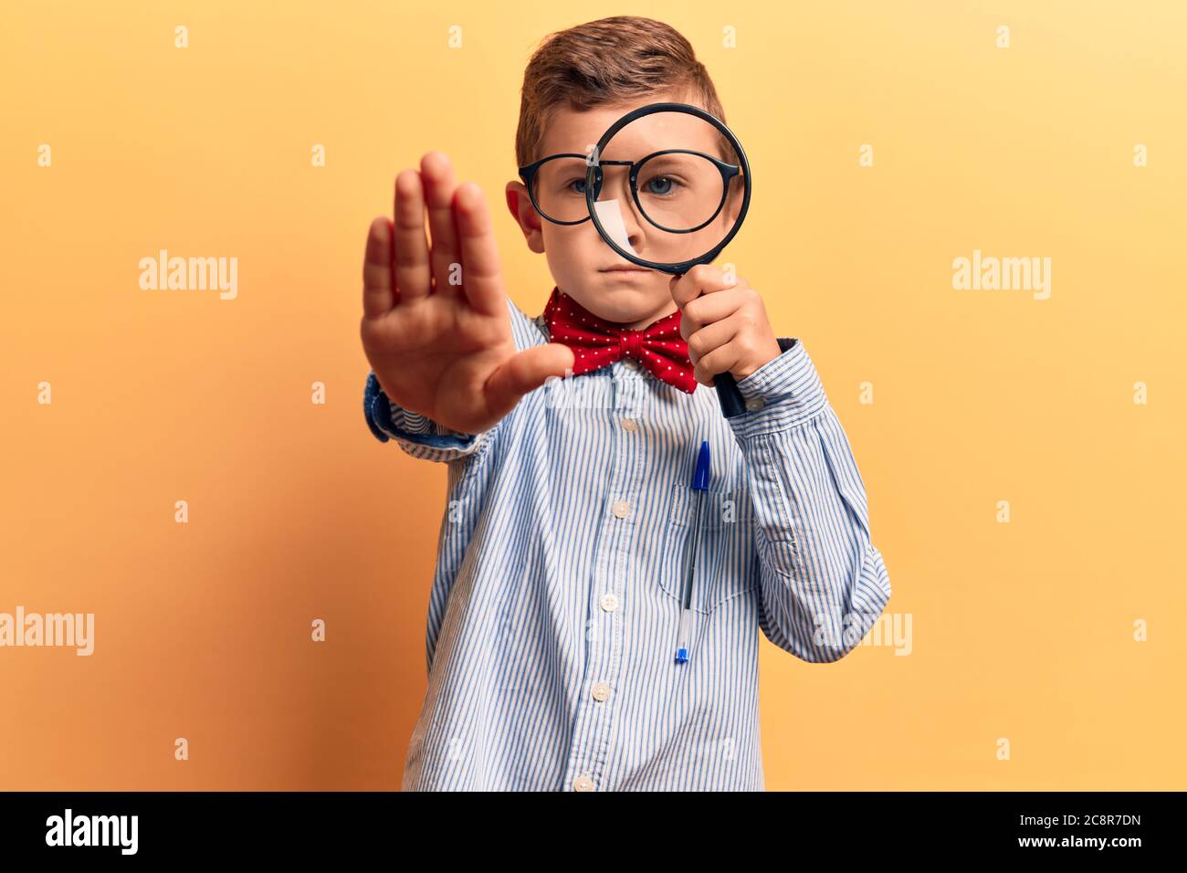 Cute blond kid wearing nerd bow tie and glasses holding magnifying ...