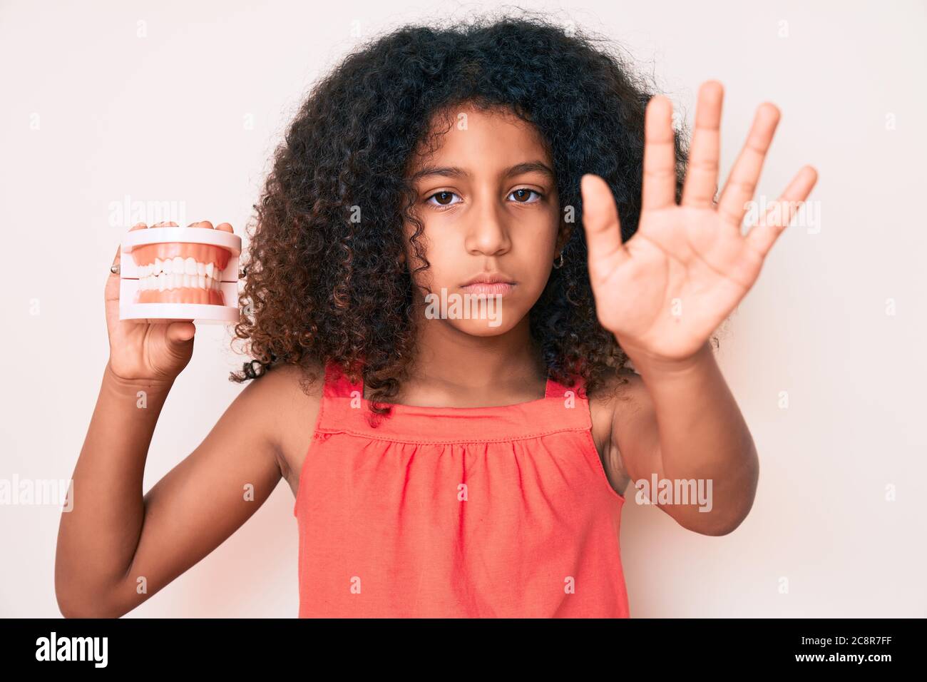 African american child with curly hair holding denture with open hand ...