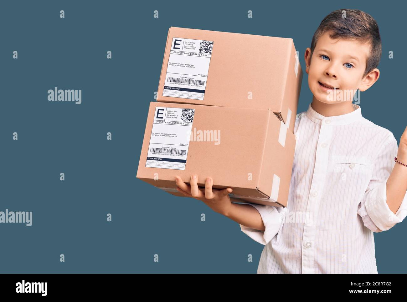 Cute blond kid holding delivery package surprised with an idea or ...