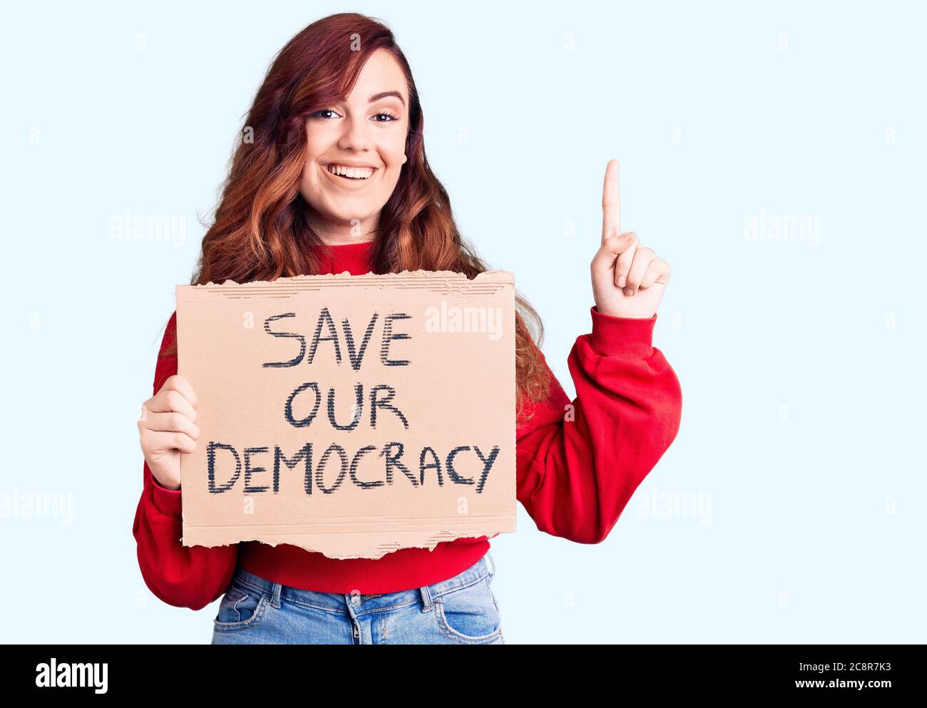 Young beautiful woman holding save our democracy protest banner ...
