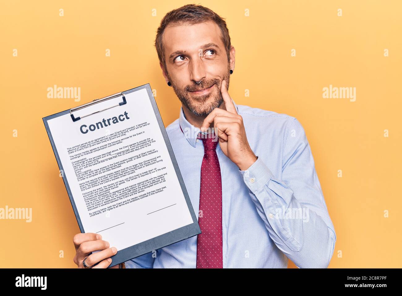 Young handsome man holding clipboard with contract document serious ...