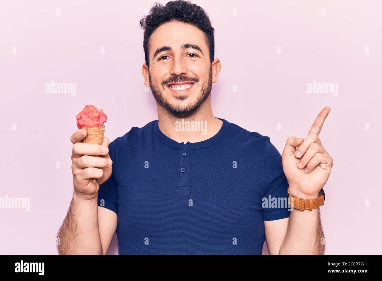 Young hispanic man holding ice cream smiling happy pointing with hand ...