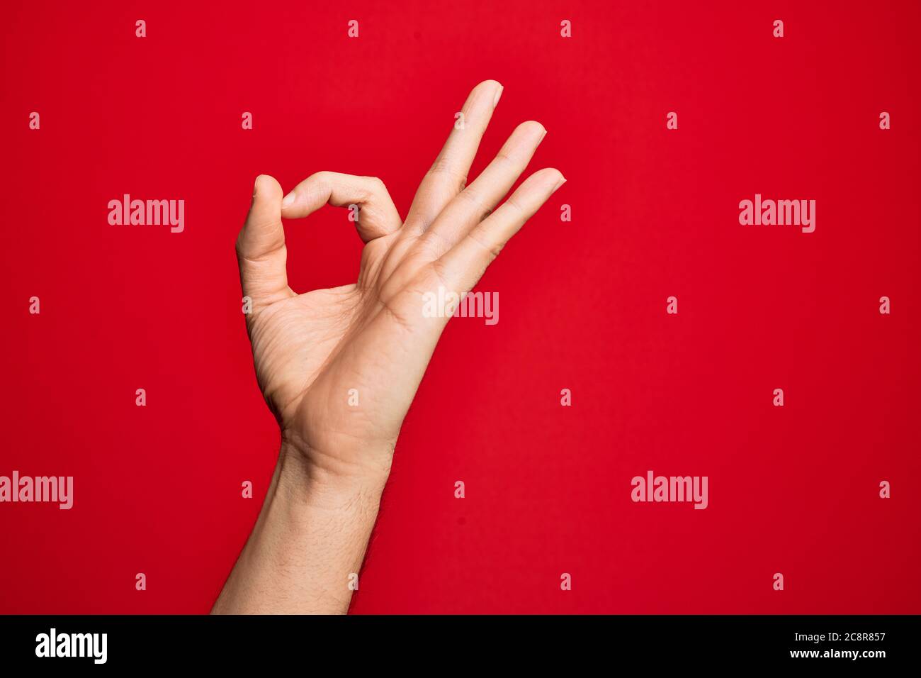 Hand of caucasian young man showing fingers over isolated red ...