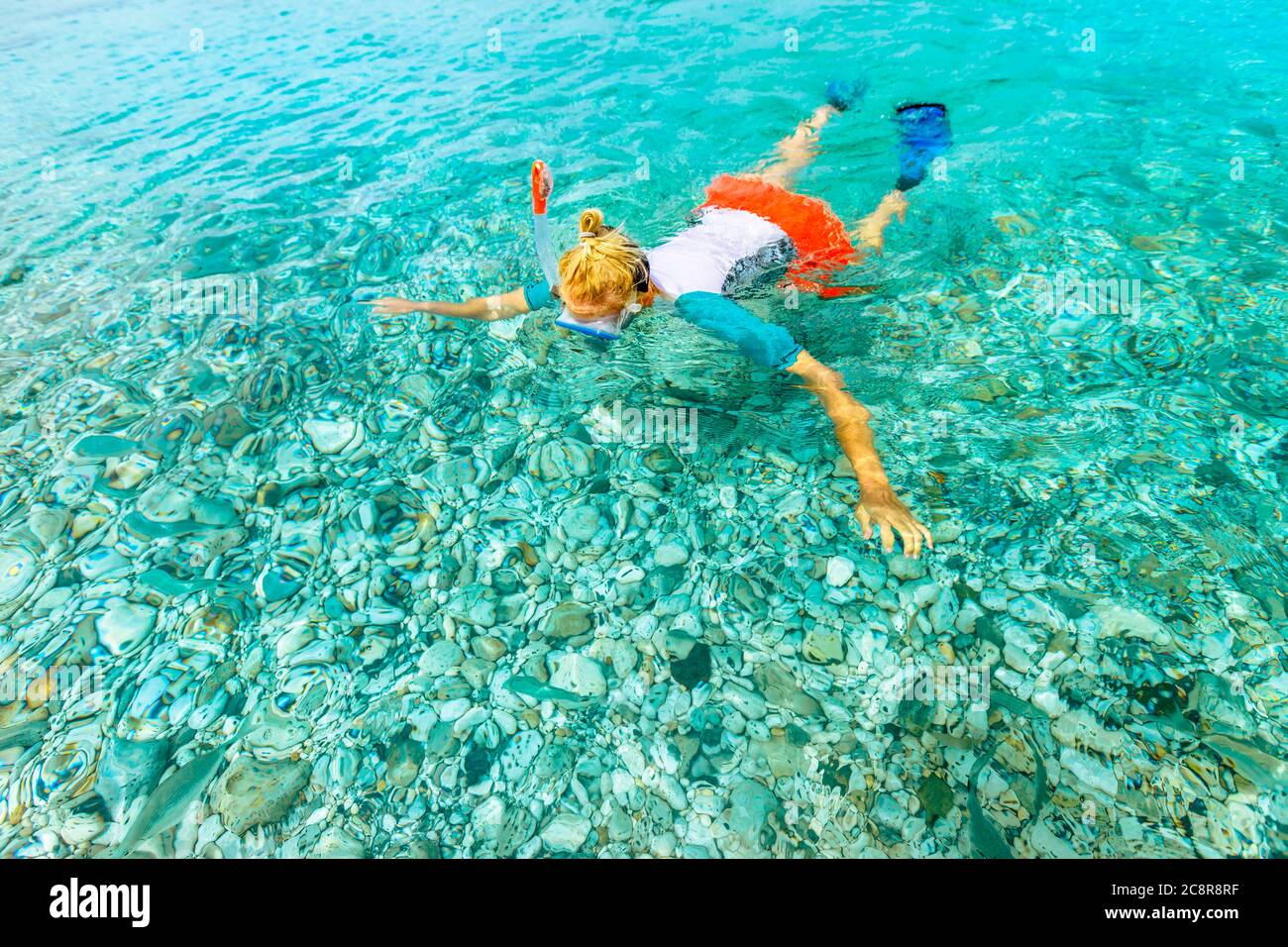 Top view of snorkeling woman in wetsuit and fins in turquoise clear ...