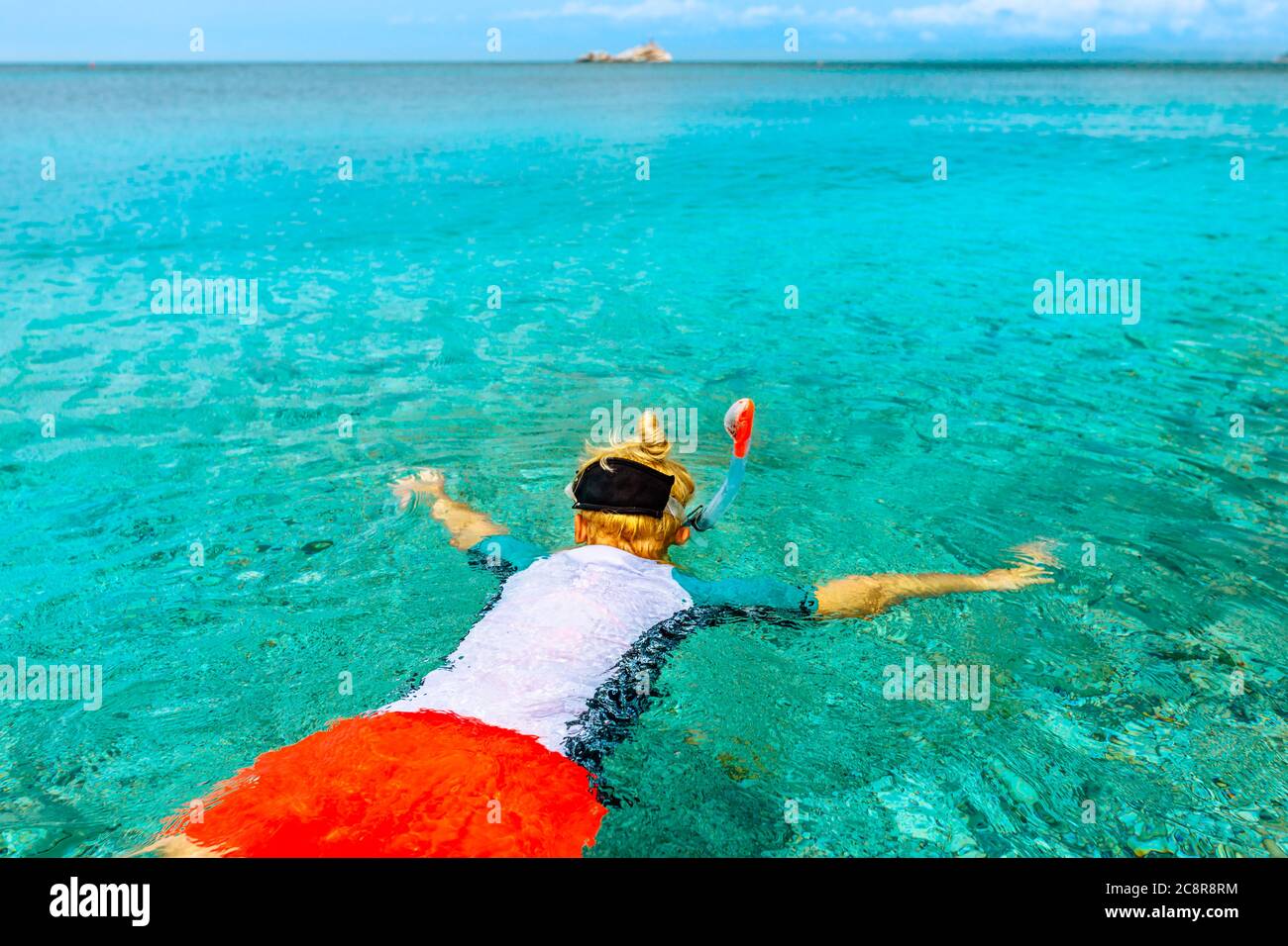 Snorkeling woman in wetsuit swimming turquoise clear waters of Le ...