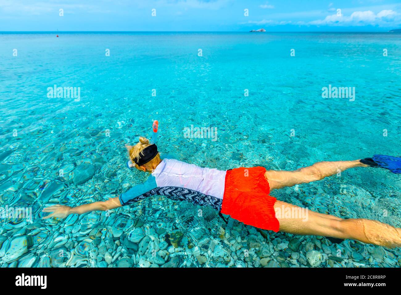 Snorkeling woman in wetsuit and fins in turquoise clear waters of Le ...